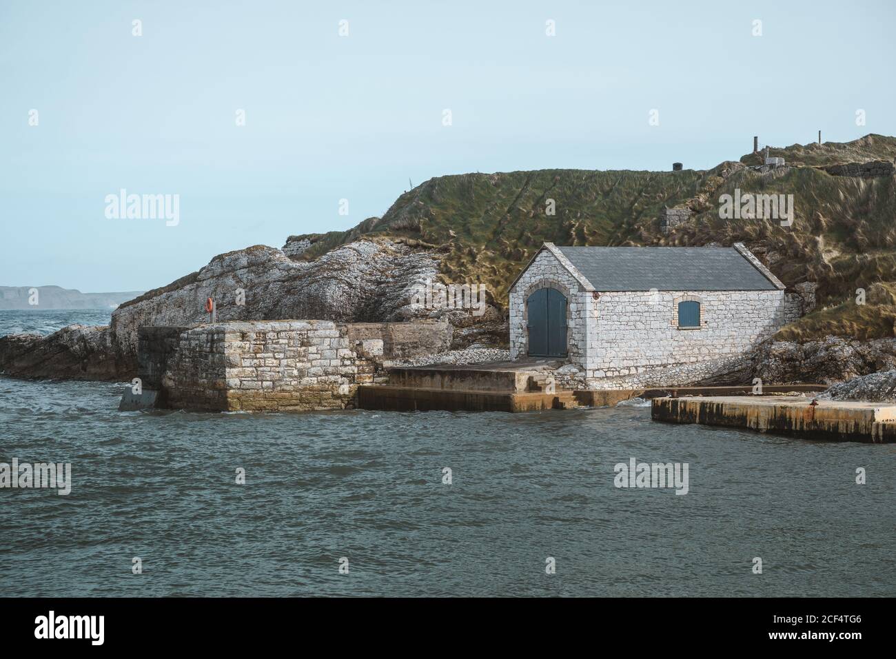 Ancient stone building with doors on picturesque pier of Ballintoy ...