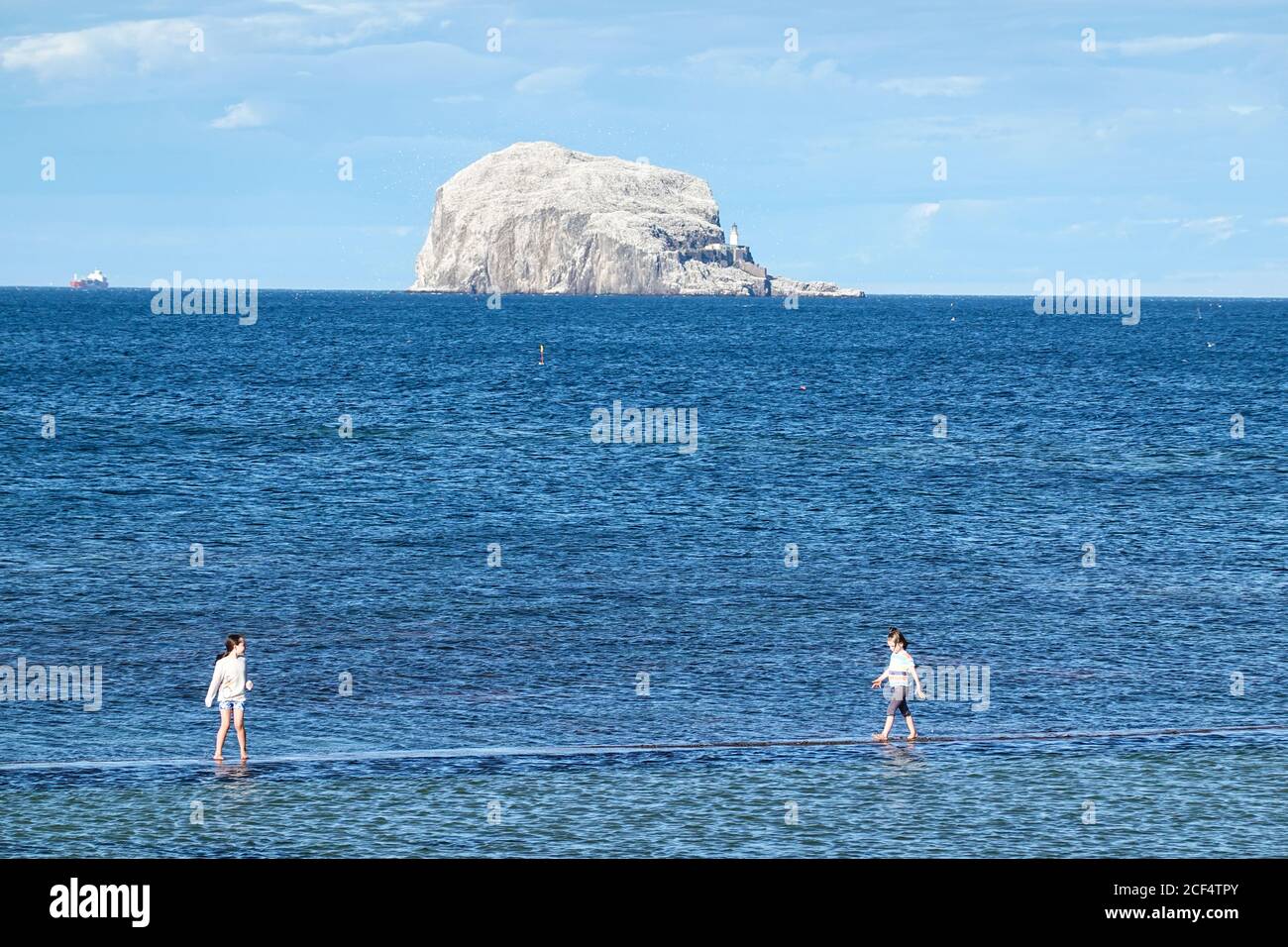 Bass Rock with people walking round paddling pool at North Berwick ...