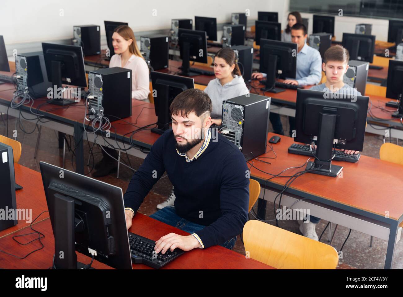 Portrait of cheerful young students at computers in university computer ...