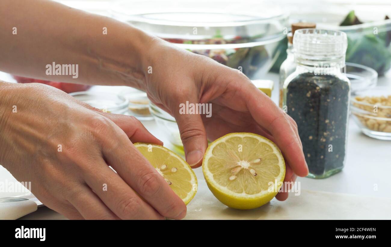 Chef cuts lemon in half. Salad dressing recipe, ingredient close up on ...