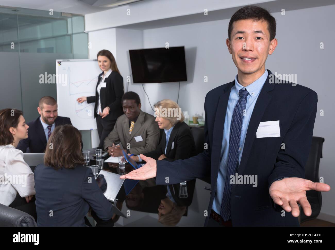 Smiling chinese businessman inviting to meeting room with business ...