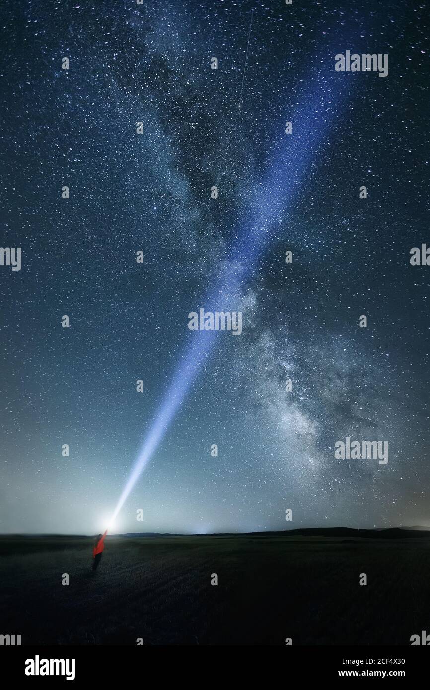 Night sky with majestic Milky way and person with bright upward beam of ...
