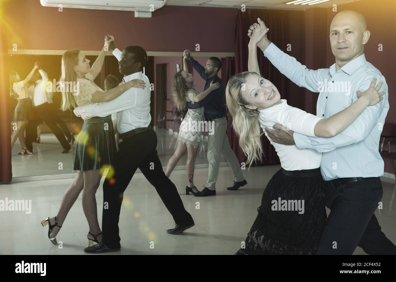 Young positive people dancing together slow ballroom dances in pairs ...
