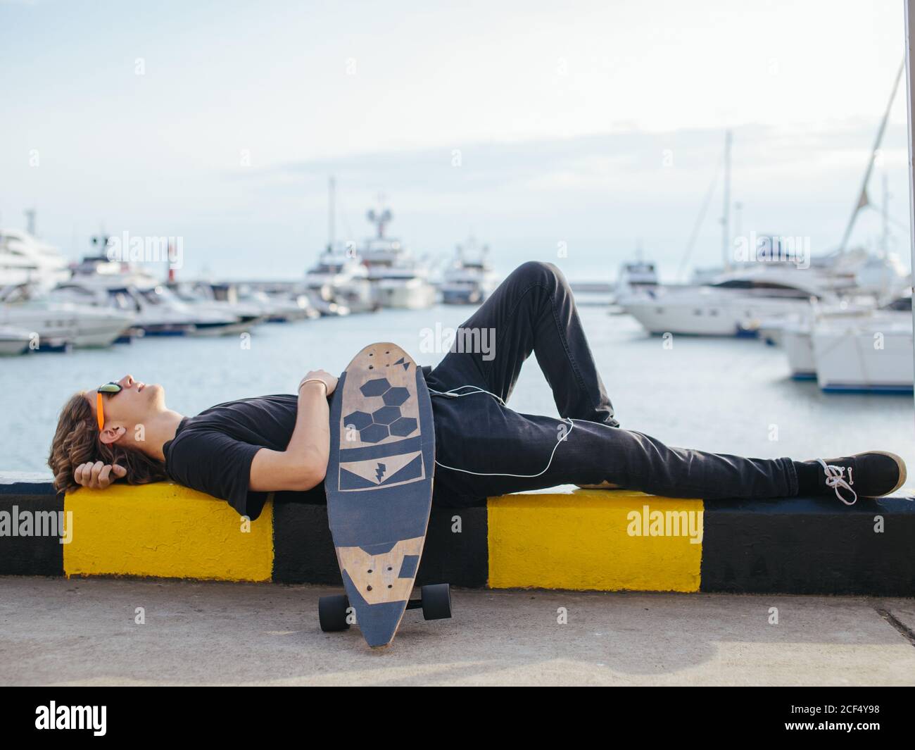 Portrait of young guy lying on skateboard spending time at skatepark ...
