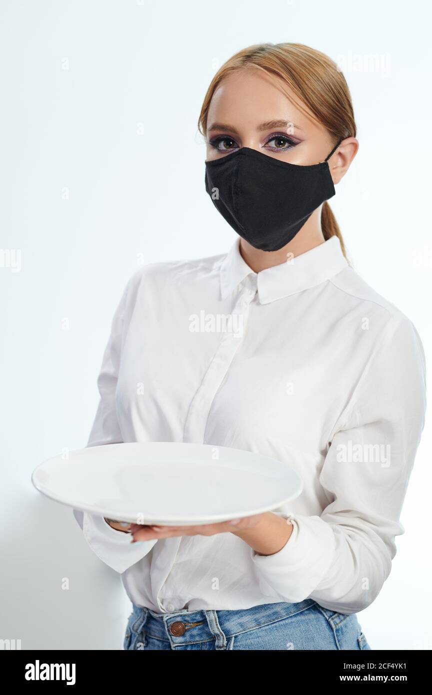 Portrait of waitress in black mask isolated on white studio background ...
