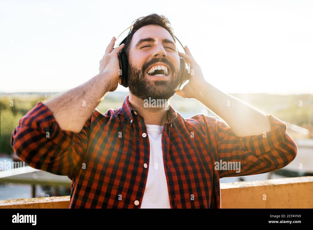 A portrait of a young man while listening to music outside. He is ...