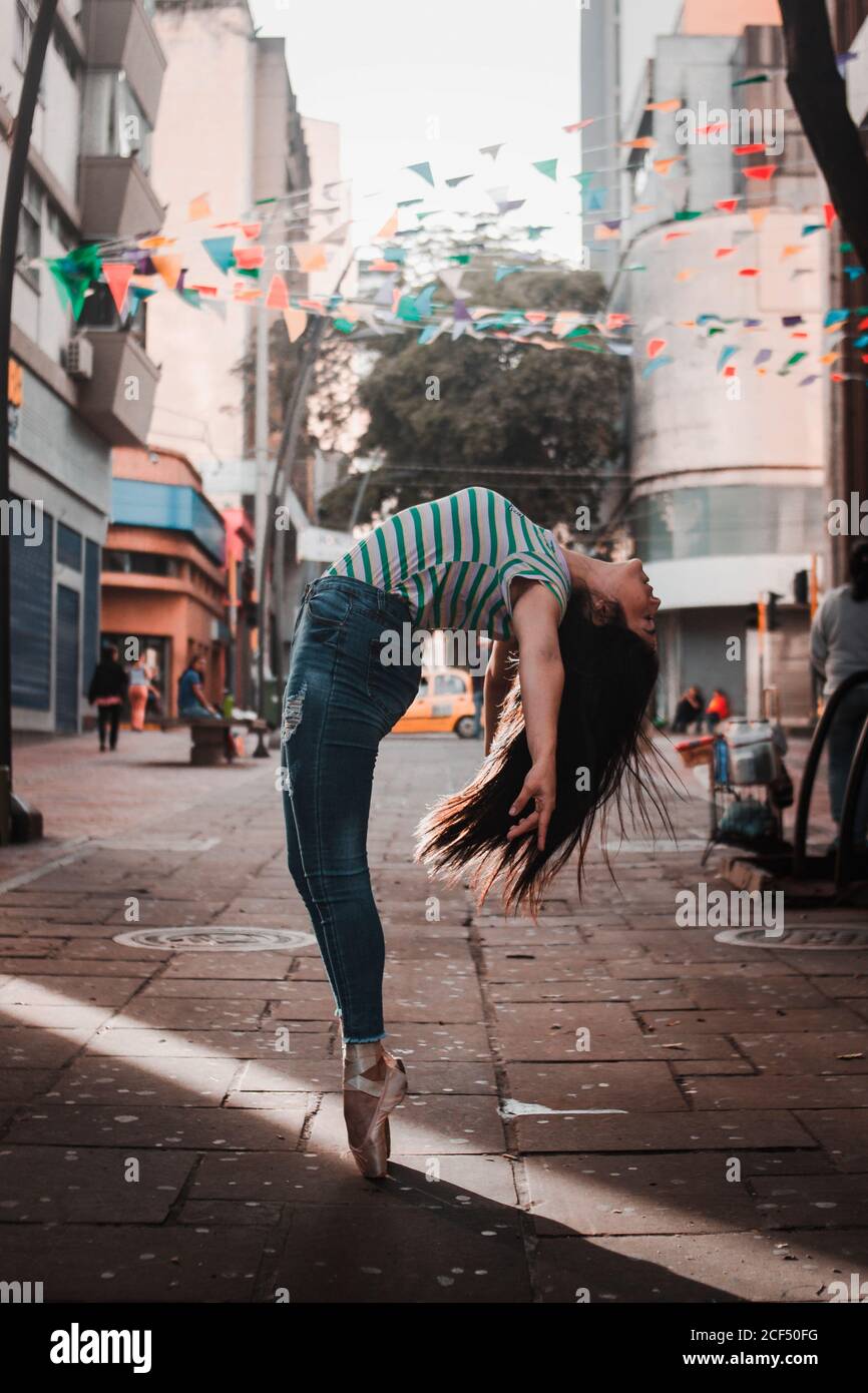 Happy female in casual clothes doing back bend while dancing on the ...