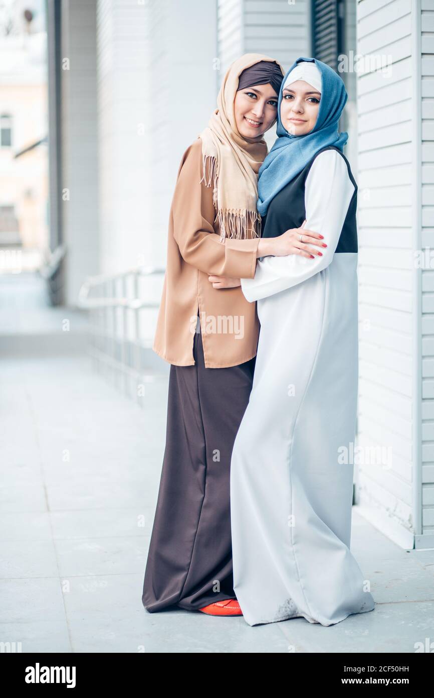two beautiful Muslim women hugging, smiling and looking at camera ...