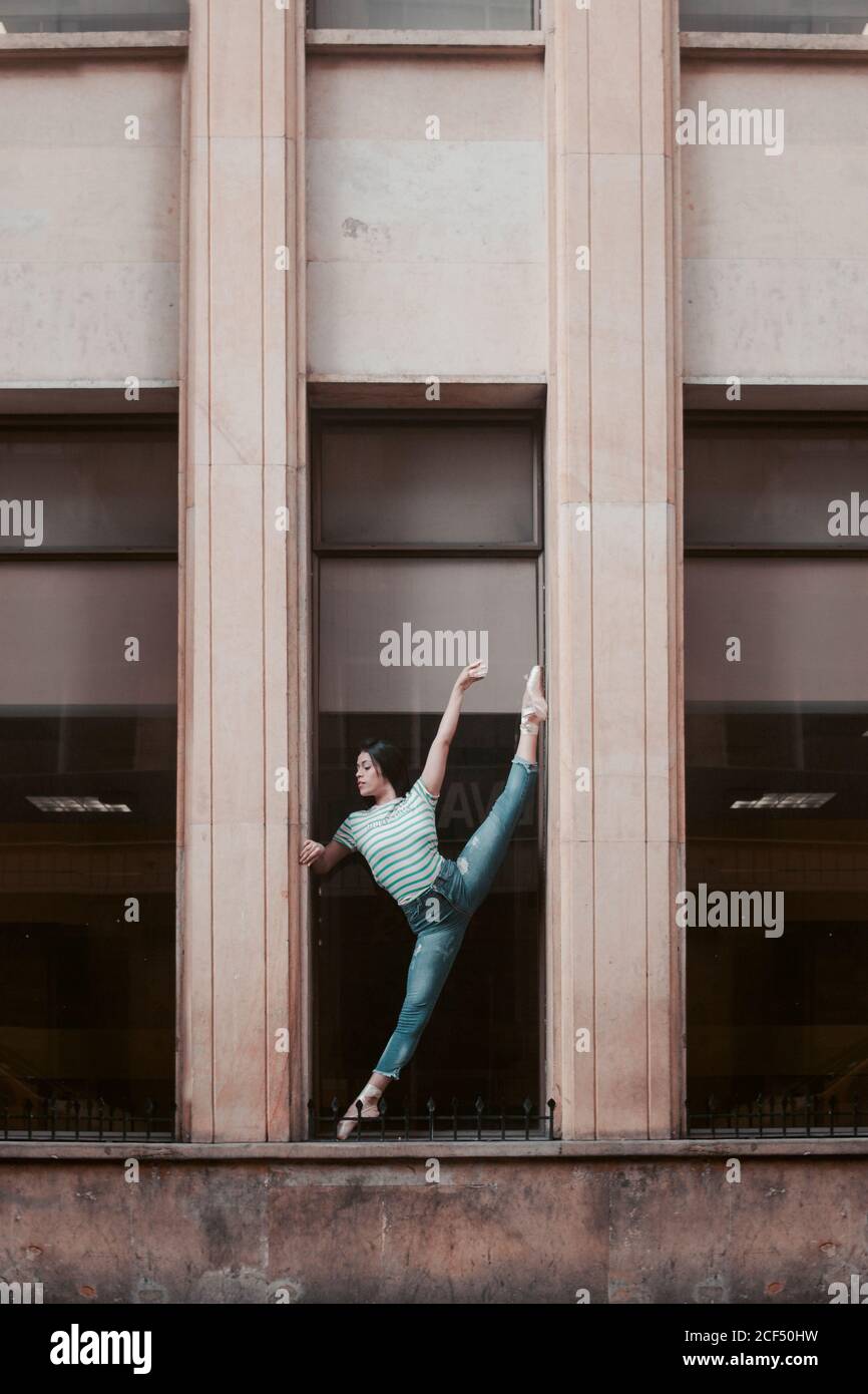 Full length slim Woman in casual clothes doing splits while stretching ...