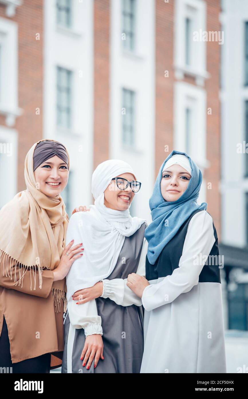 Three pretty muslim women with hijab walking in the city and laughing ...