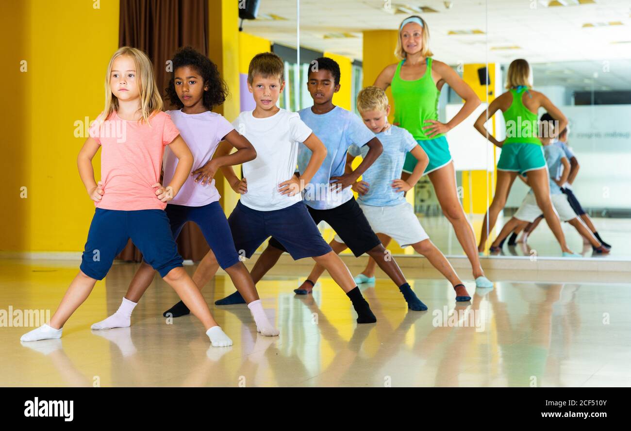 Children dancing synchronous group choreography with female coach in ...