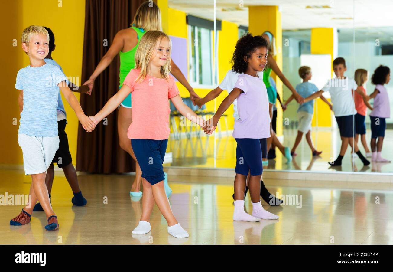 Group of kids with their teacher holding hands and dancing in circle in ...