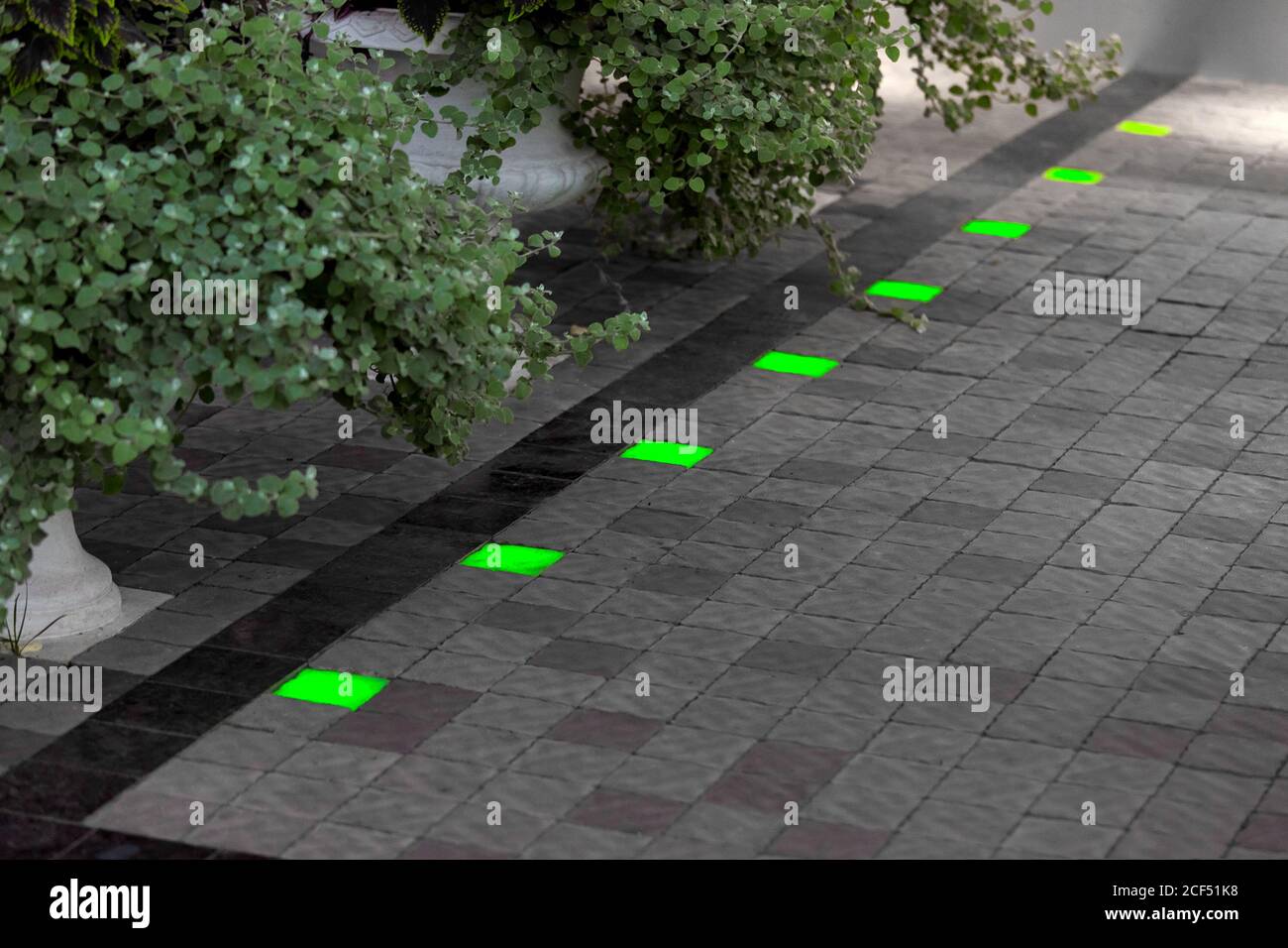 pedestrian walkway of stone tiles with square green ground lanterns set ...