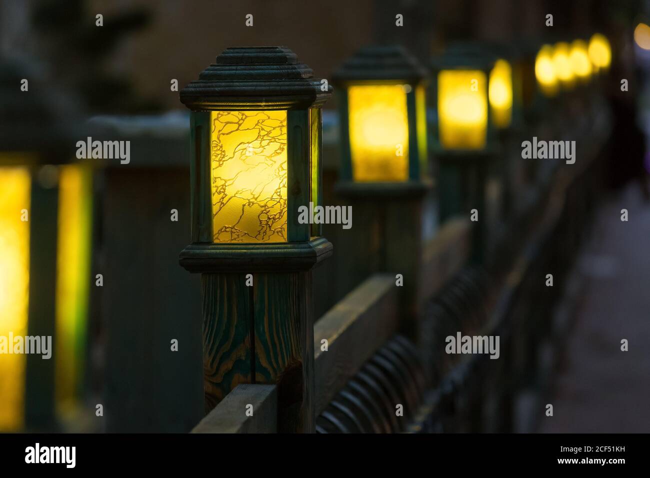 wooden street lamps with yellow glass diffuser on wooden fence of ...