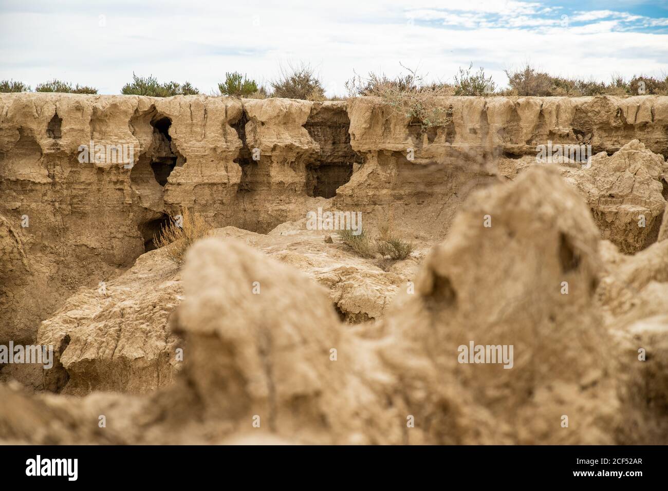 Dried big rocks with green sparse vegetation under blue sky and white ...