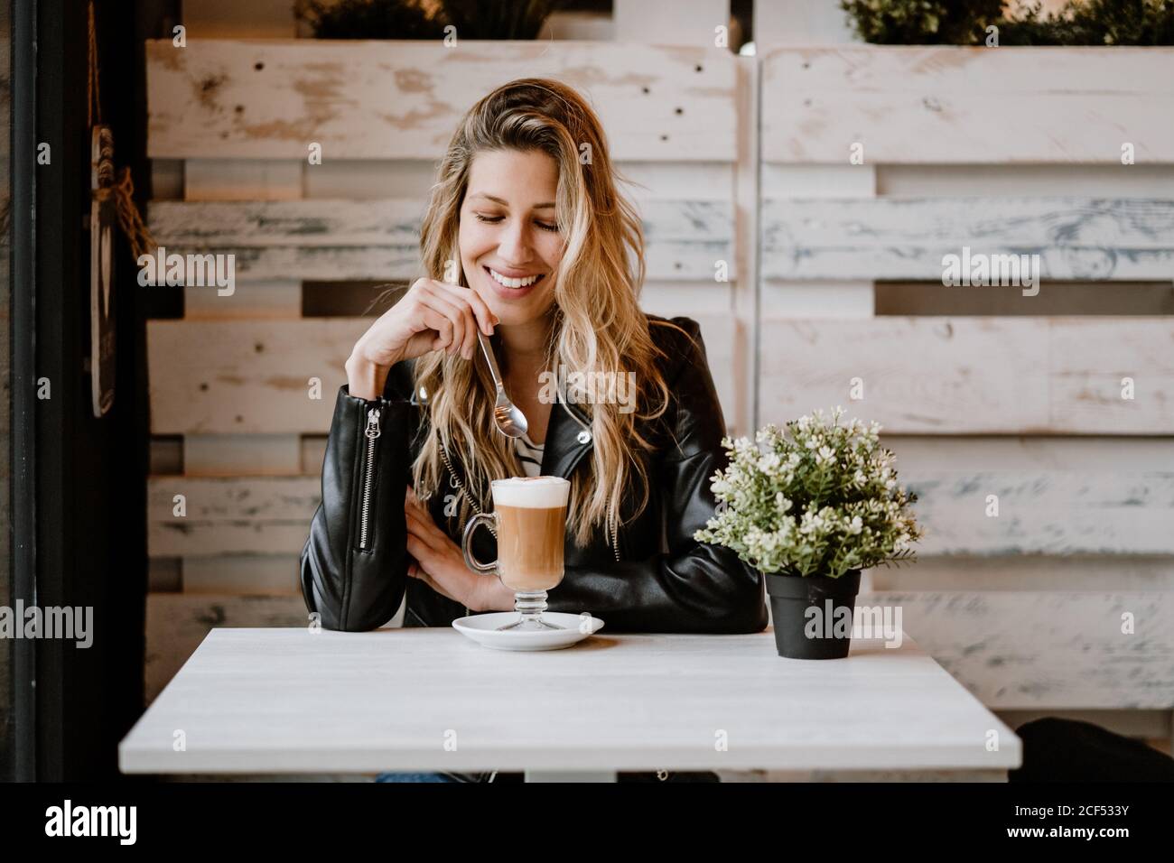Long haired trendy beautiful blonde Woman drinking from a glass of ...