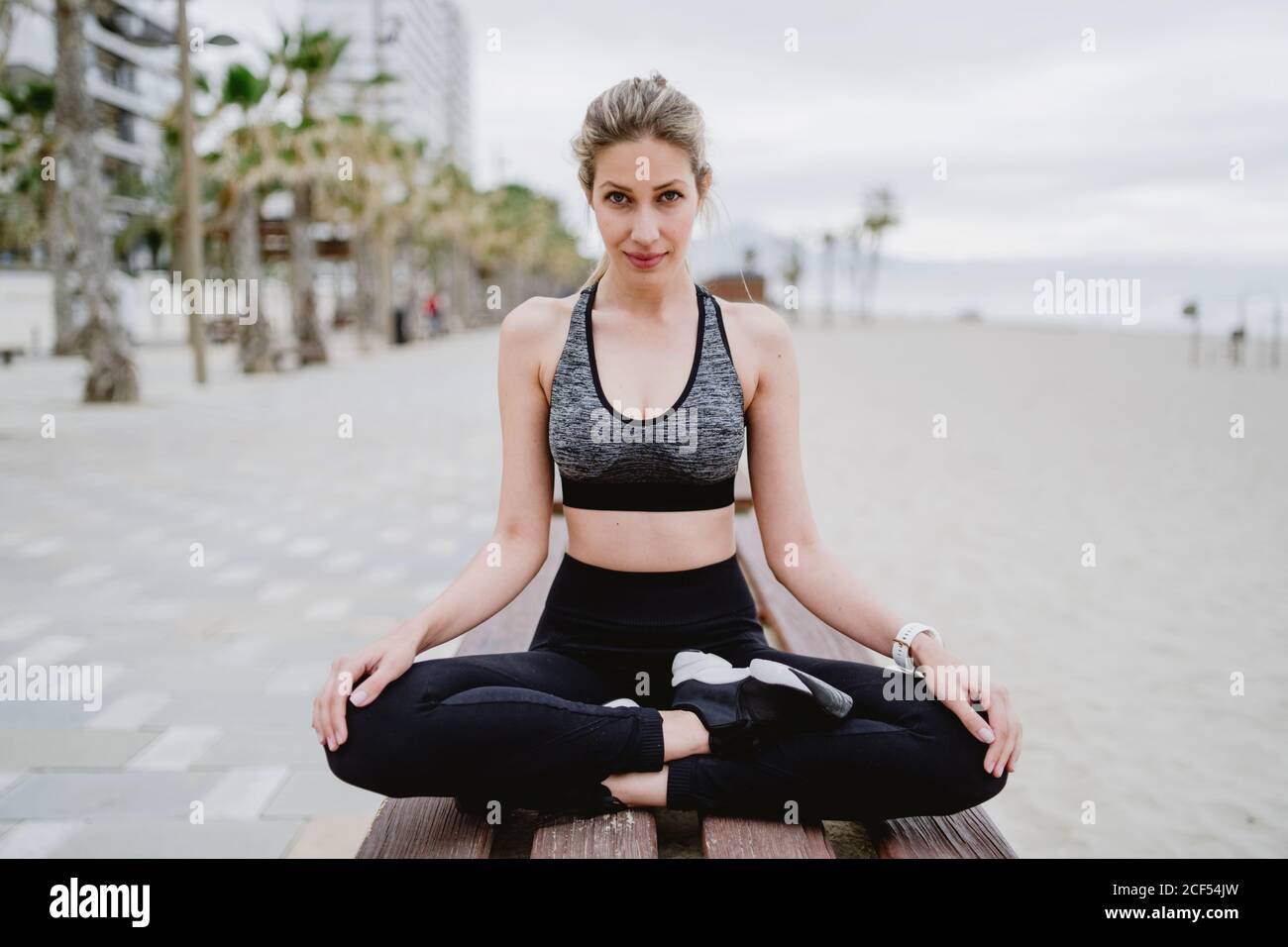 Concentrated lady athlete in trendy active wear and sneakers sitting on ...
