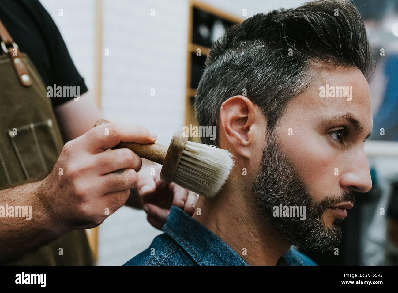 Side view of crop barber with brush near happy handsome stylish male ...