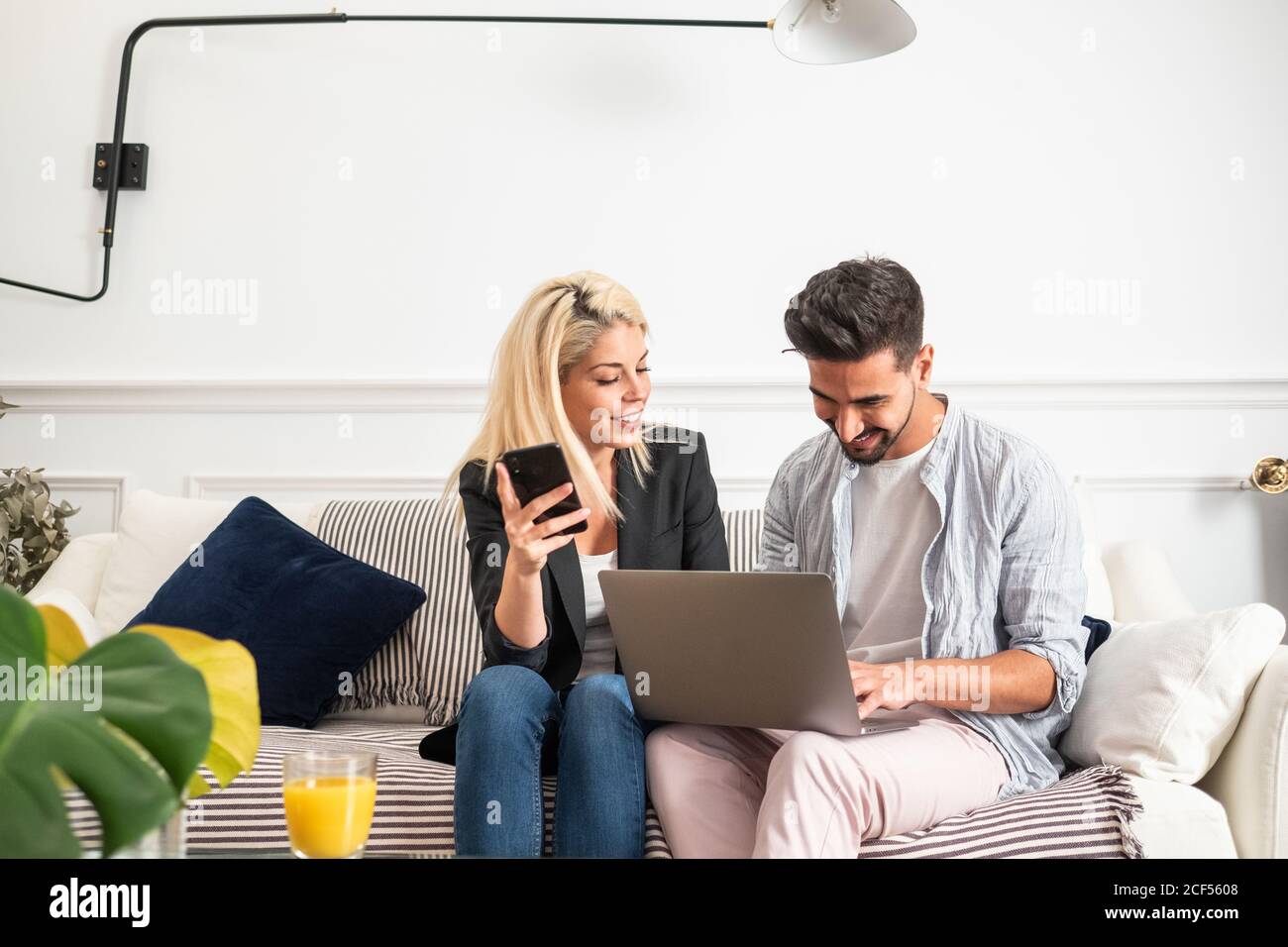 Positive blond Woman with cup of juice browsing smartphone and sitting ...