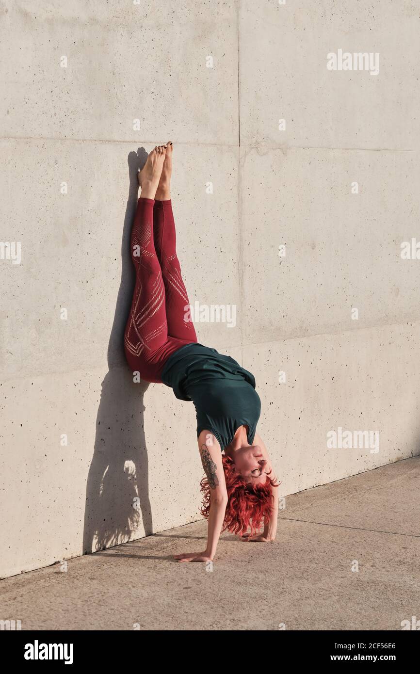 Side view of slim barefooted female with red hair in sportswear ...