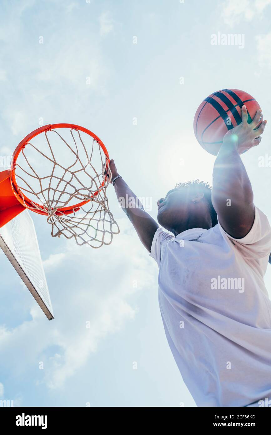 Powerful energetic African American sportsman hanging on basketball lap ...