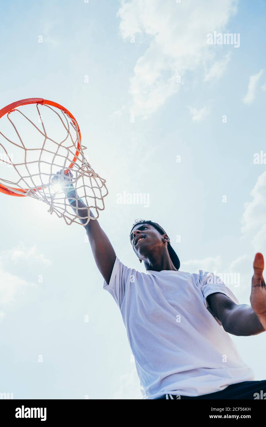 Powerful energetic African American sportsman hanging on basketball lap ...