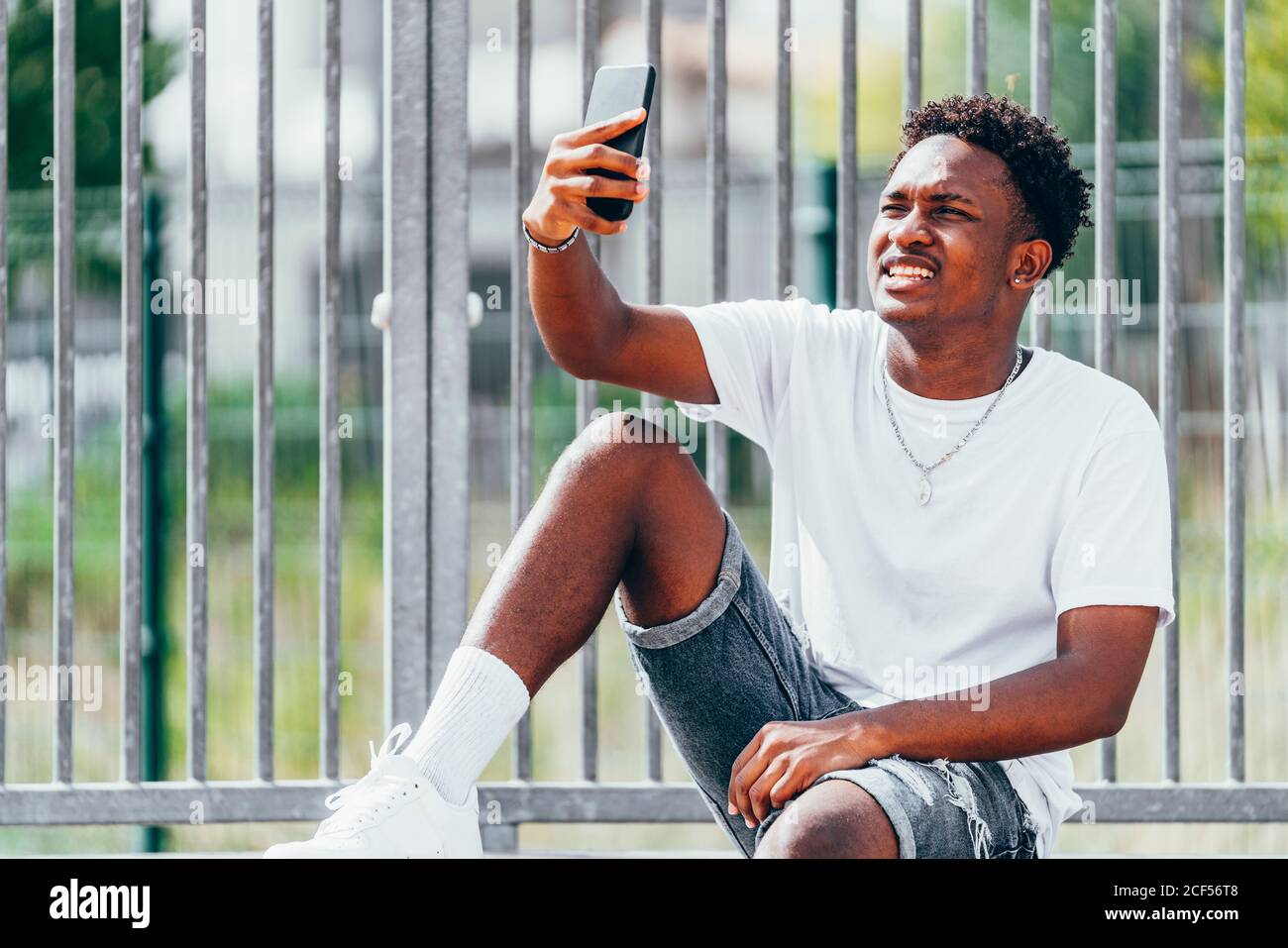 Pensive African American sportsman surfing mobile phone comfortable ...