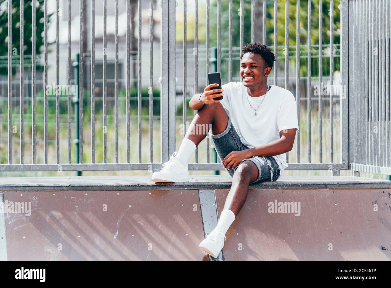 Pensive African American sportsman surfing mobile phone comfortable ...