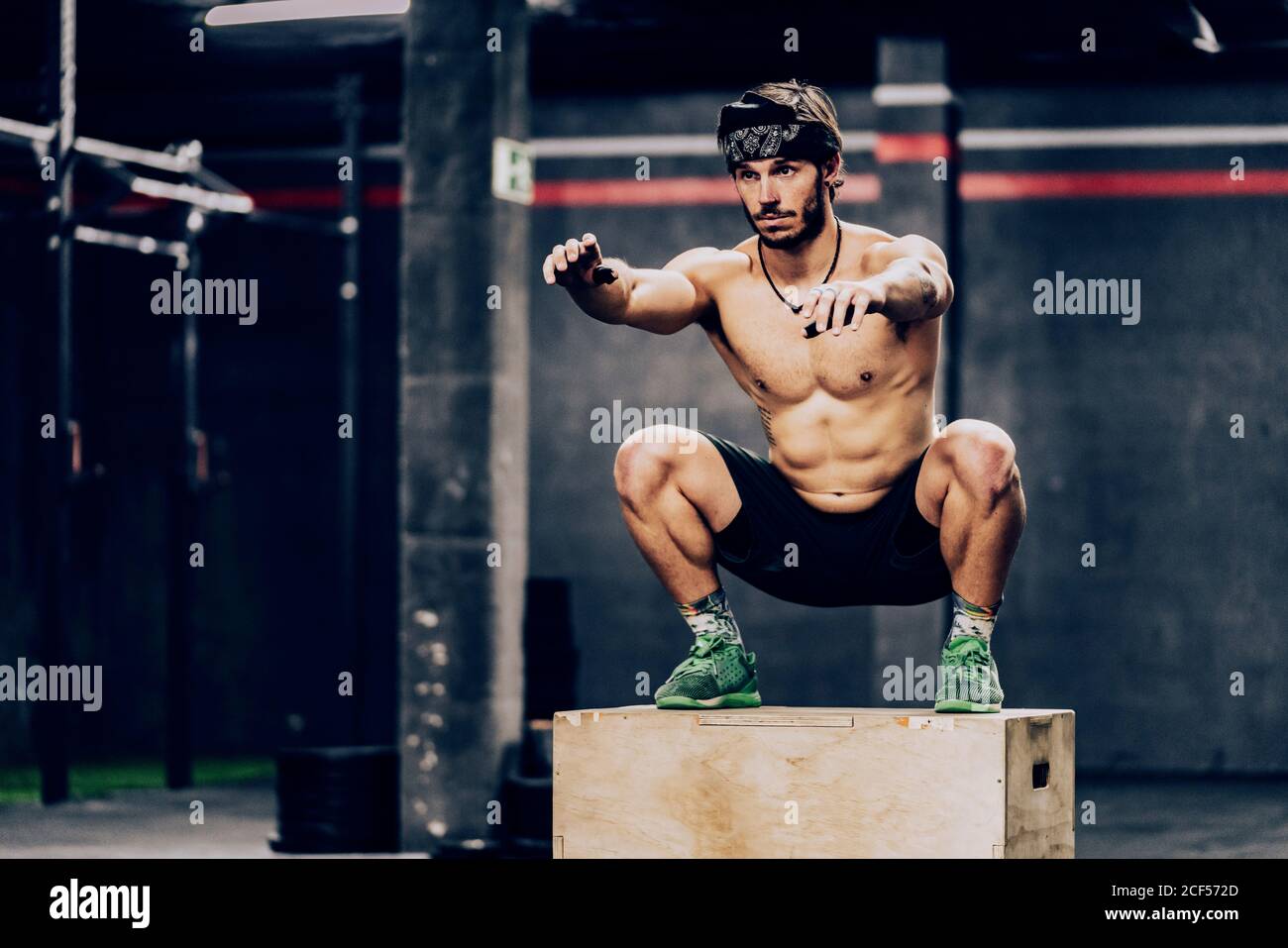 Athletic man jumping on box to improve stamina in gym Stock Photo - Alamy