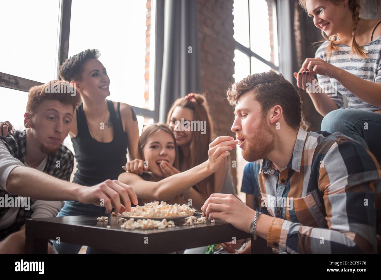 Young women throwing popcorn at male friend Stock Photo - Alamy