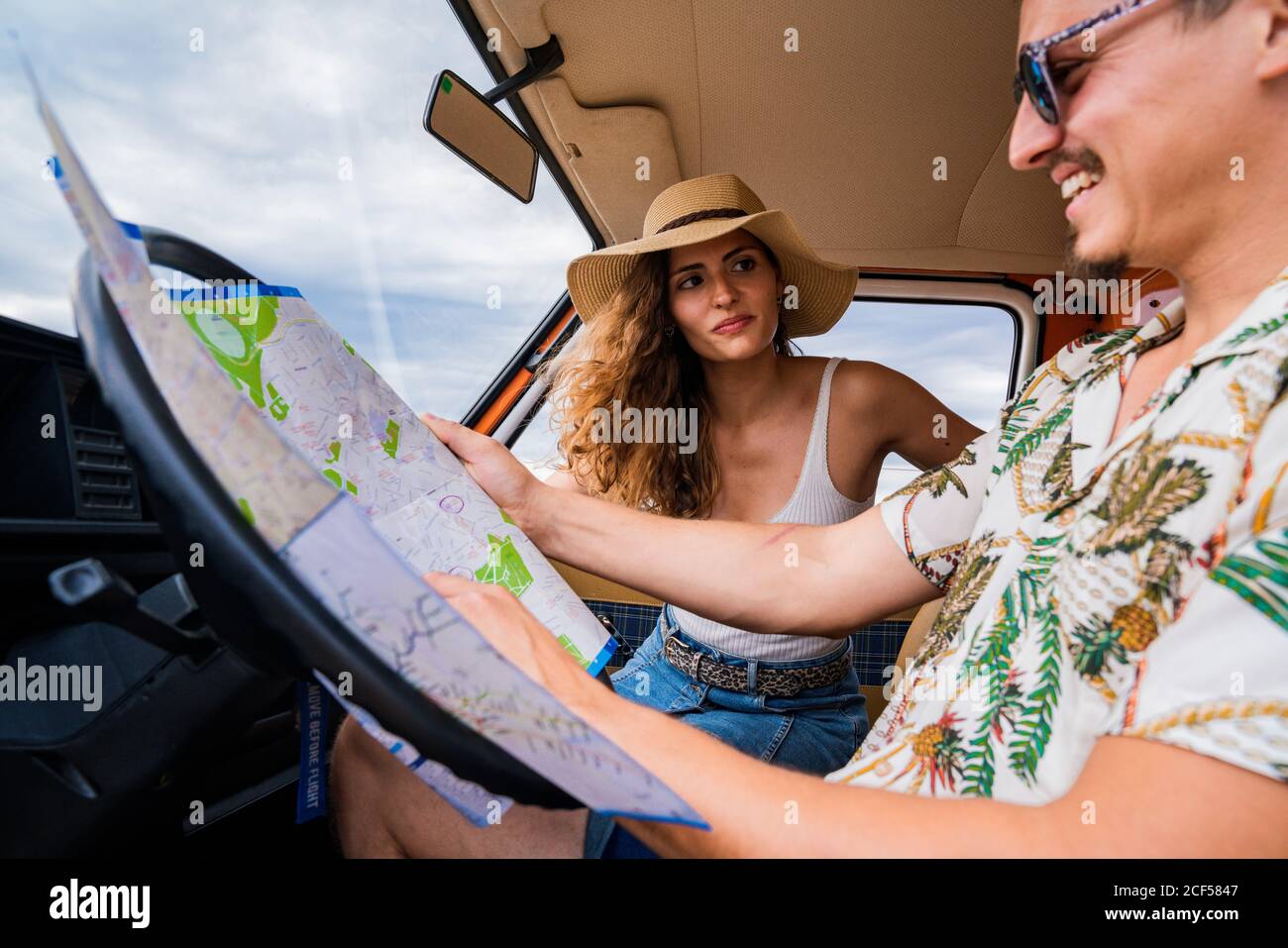 Side view of active smiling man in sunglasses looking at open road map ...
