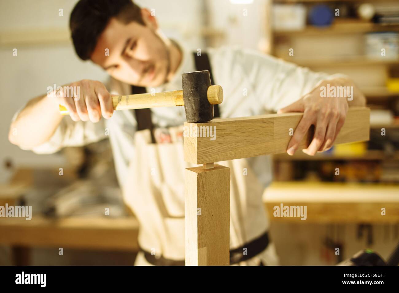Man with mallet joining two parts of wooden planks. Worker carpenter ...