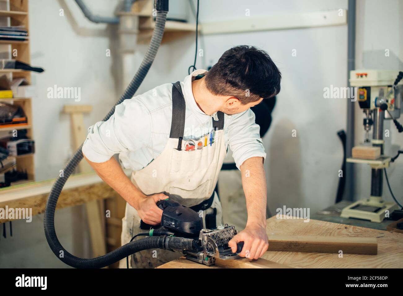 Carpenter using power-tool for cutting wood in carpentry workshop Stock ...