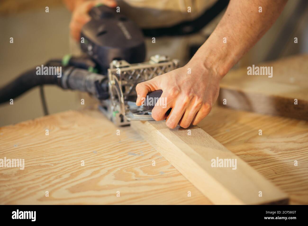 Carpenter using power-tool for cutting wood in carpentry workshop Stock ...