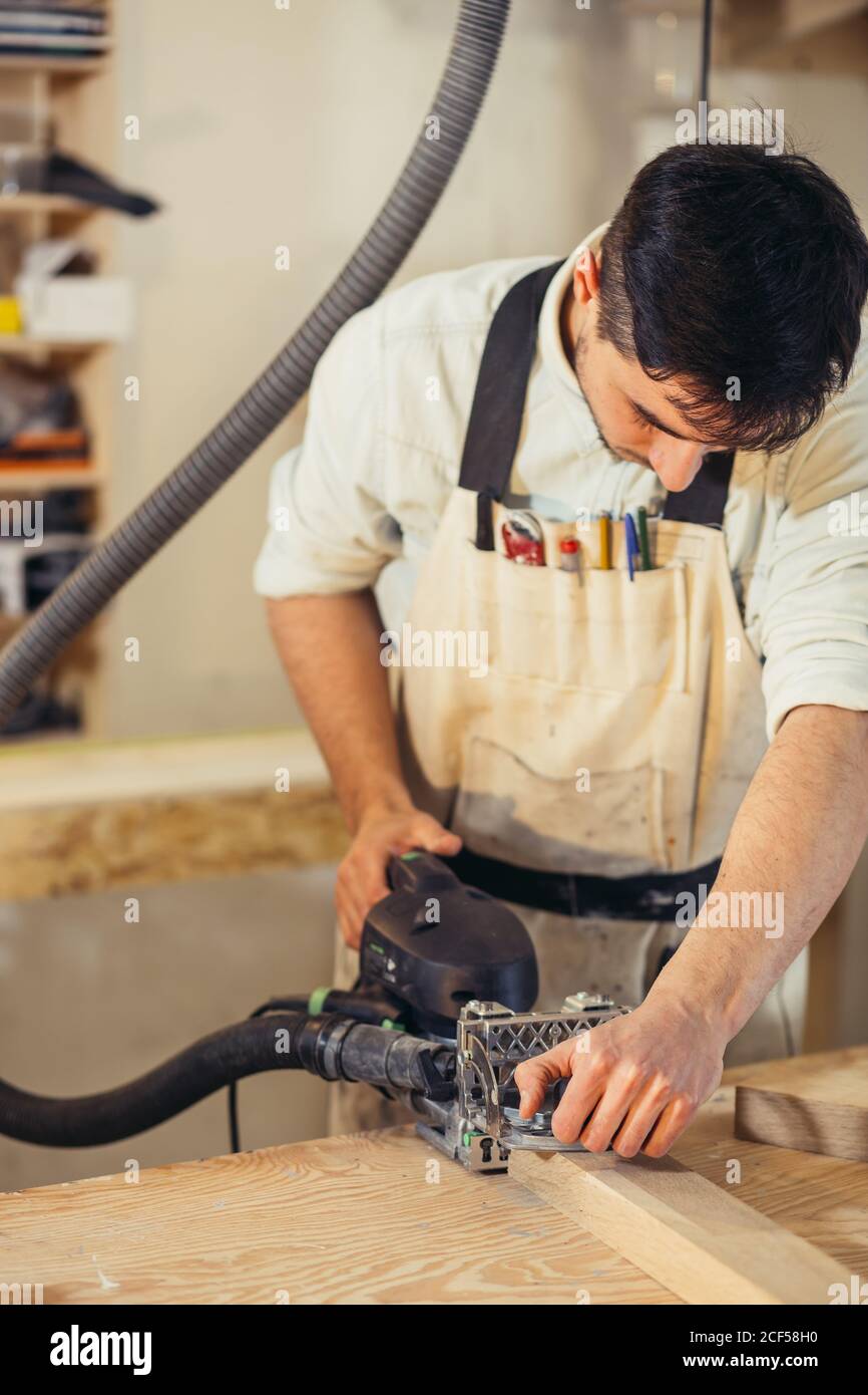 Carpenter using power-tool for cutting wood in carpentry workshop Stock ...