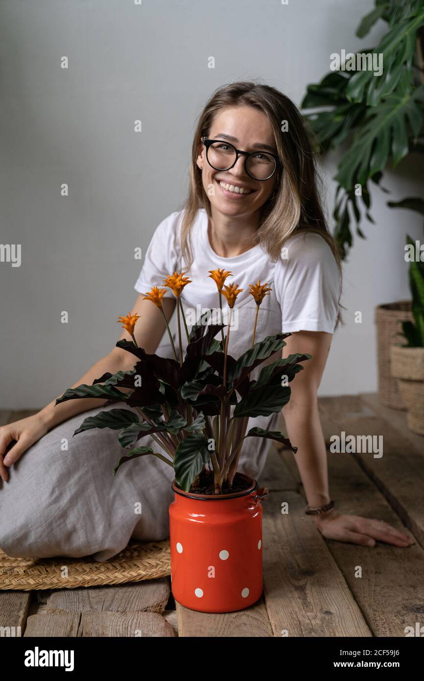 Happy woman gardener in eyeglasses wearing linen dress, sitting on the ...