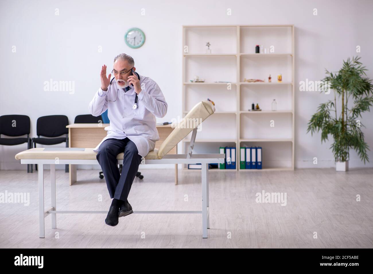 Old experienced doctor working in the clinic Stock Photo - Alamy
