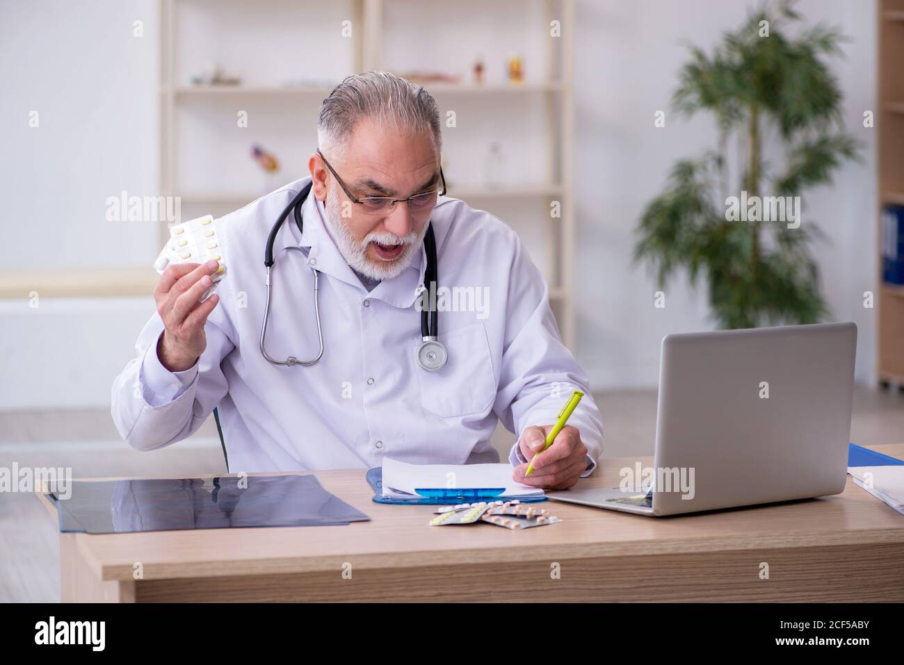 Old experienced doctor working in the clinic Stock Photo - Alamy