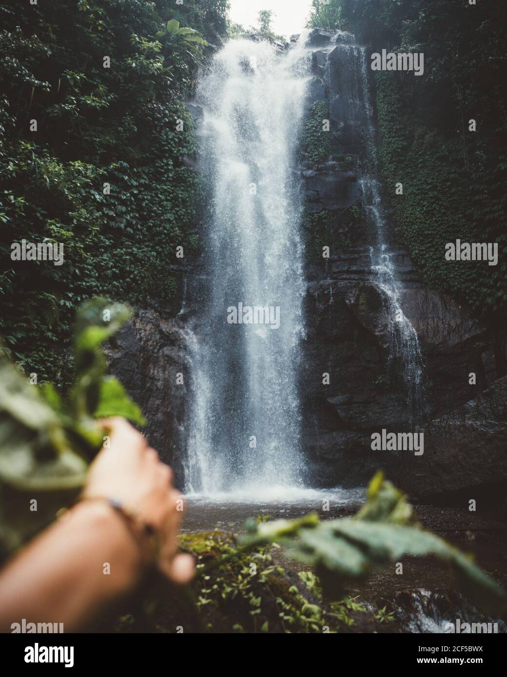Crop blurred man discovering picturesque waterfall on high cliff in ...