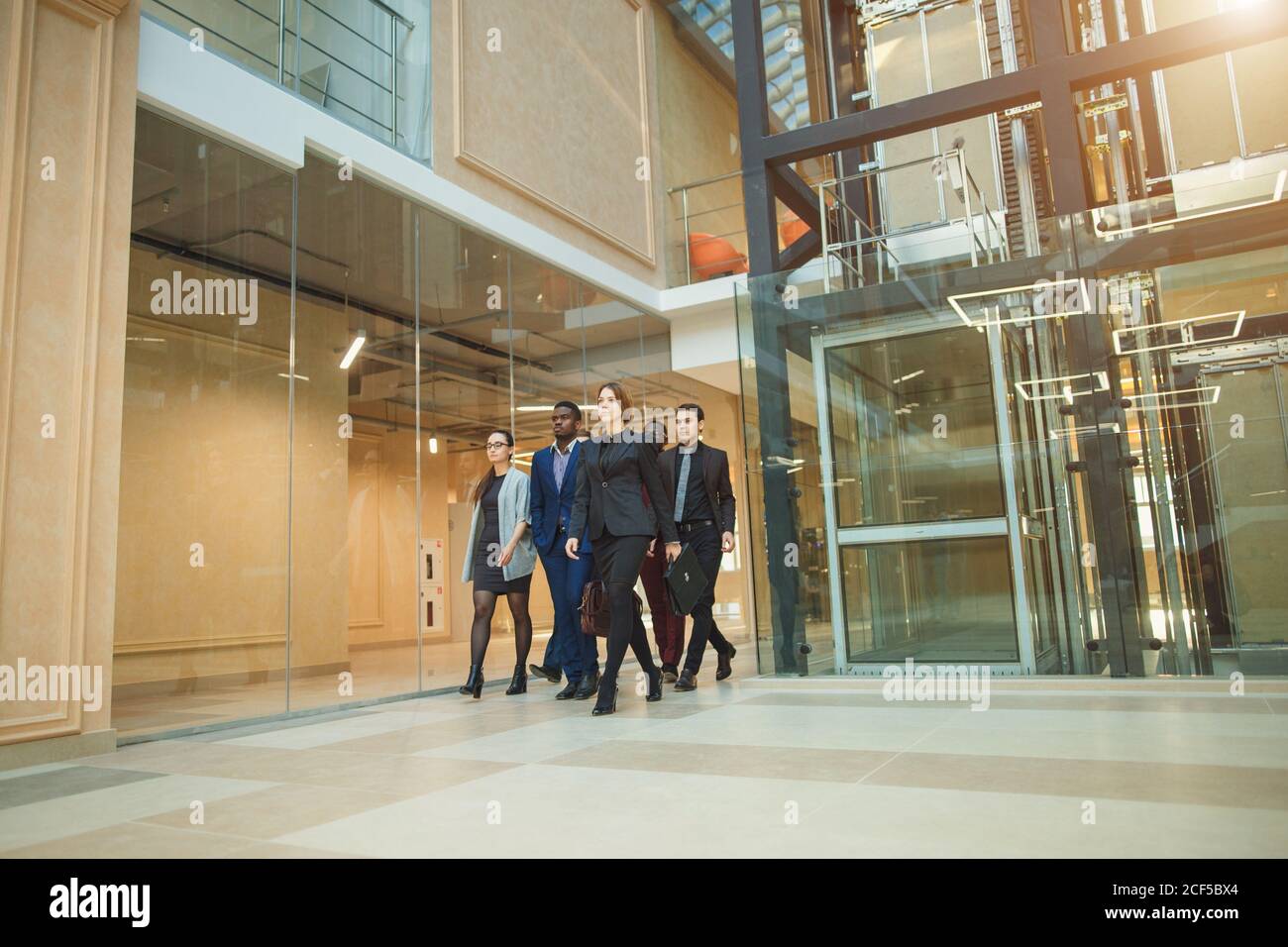 People walk in a modern office lobby interior with a meeting room with ...