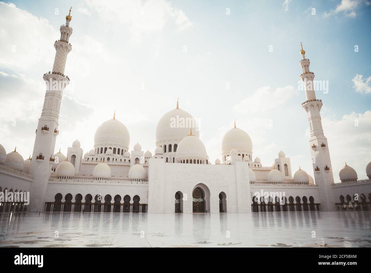Beautiful white mosque with domes and minarets under bright blue sky ...