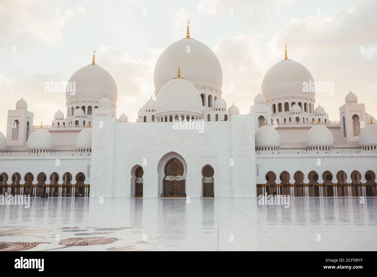 Beautiful white mosque with domes and minarets under bright blue sky ...
