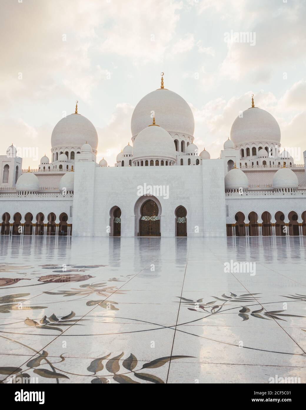 Beautiful white mosque with domes and minarets under bright blue sky ...