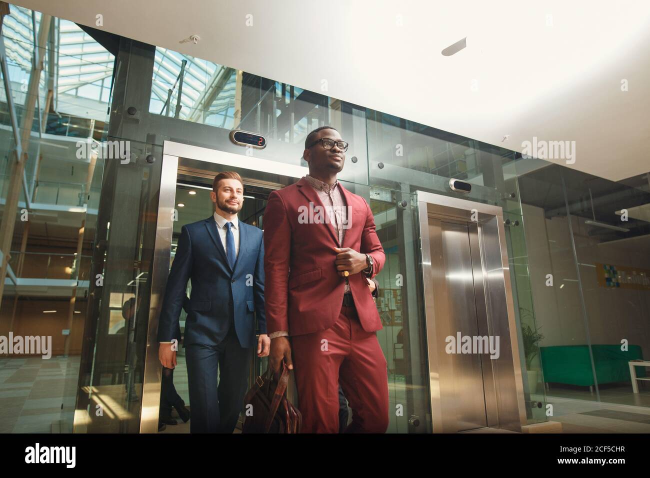 Business team group exit on elevator. Business people in a large glass ...