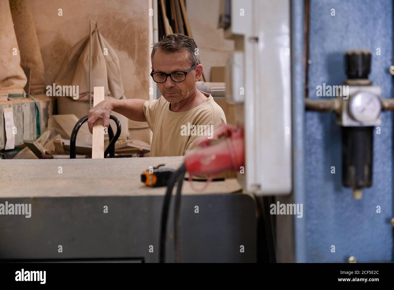 Attentive middle aged workman in glasses and casual clothes focusing ...