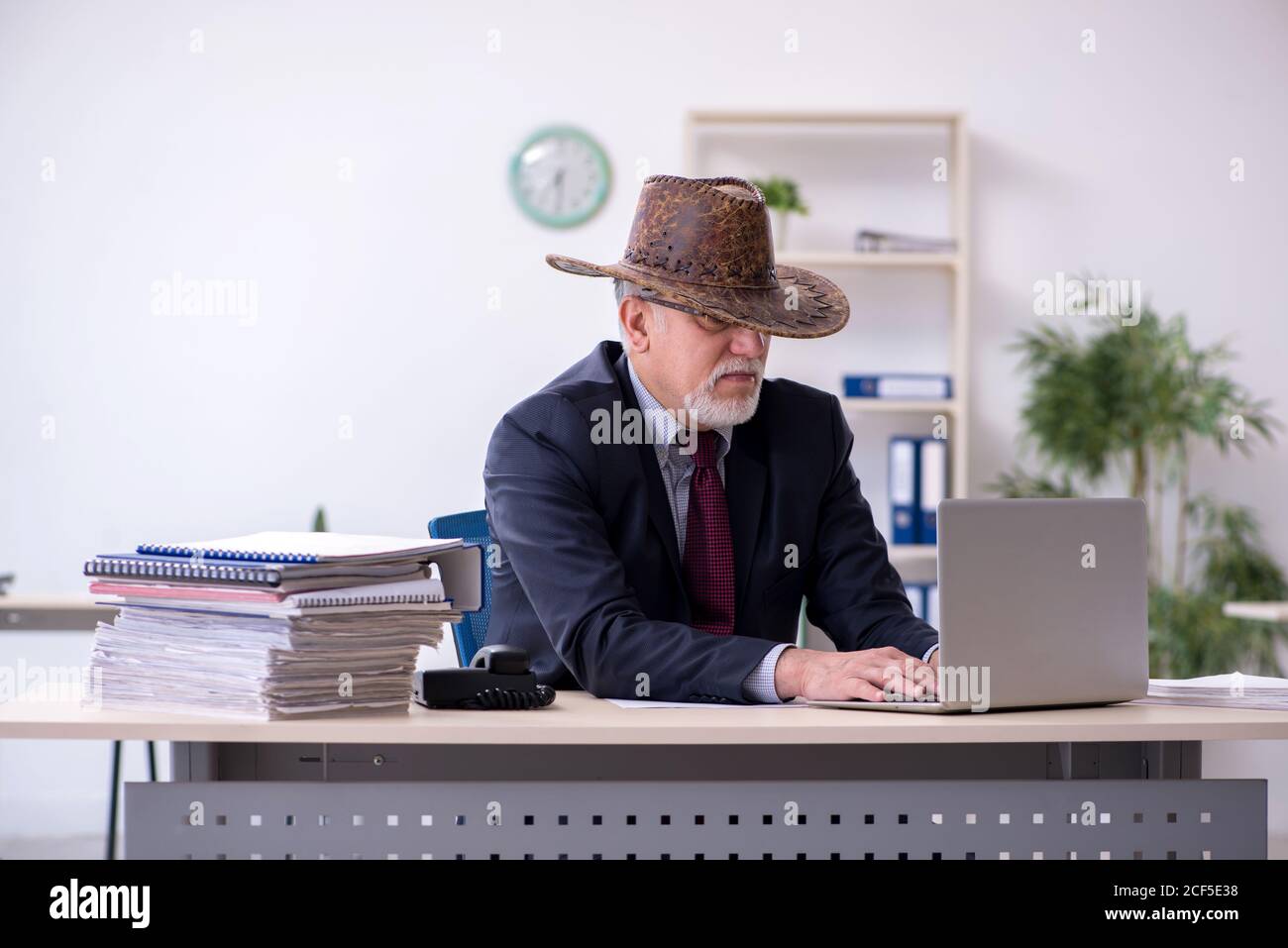 Funny old boss in cowboy hat in office Stock Photo - Alamy
