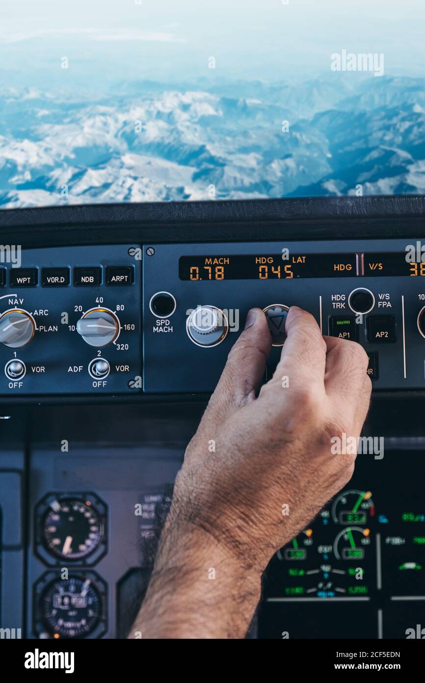 Back view of crop anonymous male pilot turning switch on control panel ...
