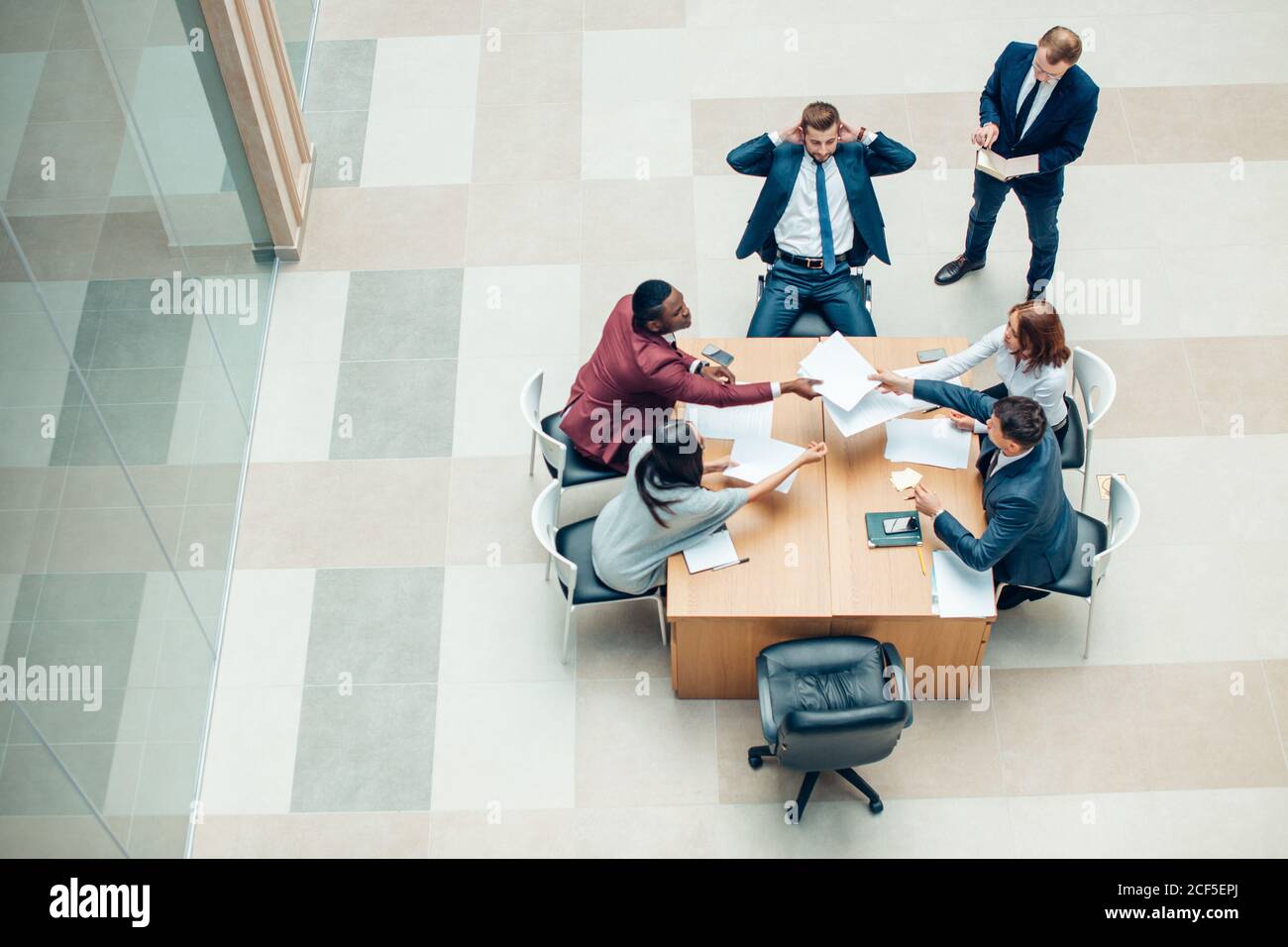 Office workers gather around a table to do research and implement new ...