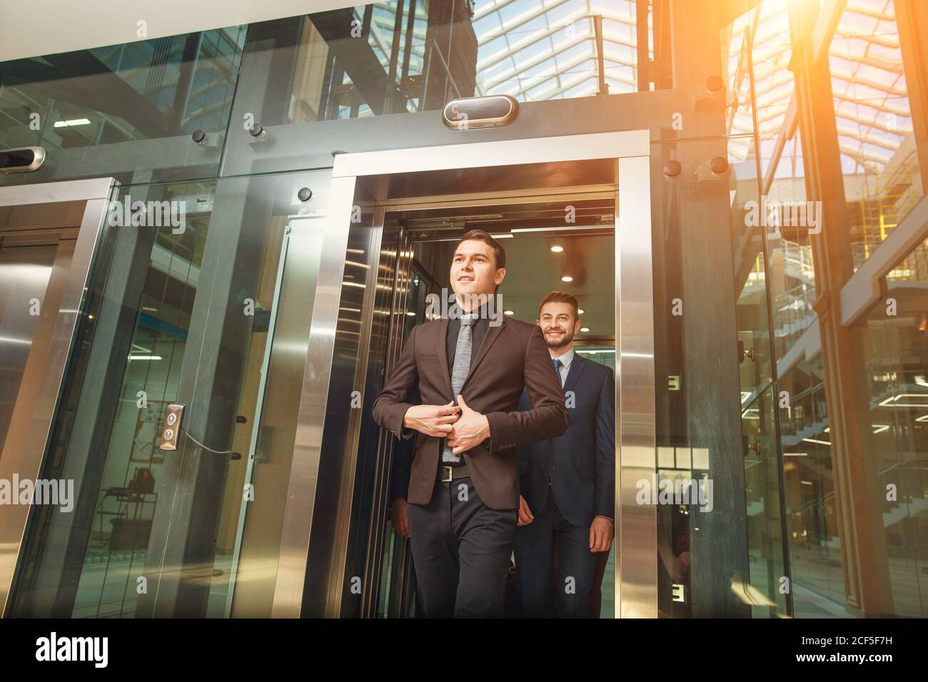 Business team group exit on elevator. Business people in a large glass ...