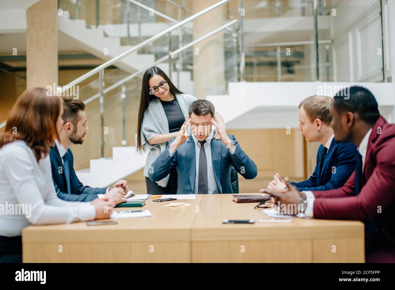 Businessman having headache during a business meeting - Depressed ...